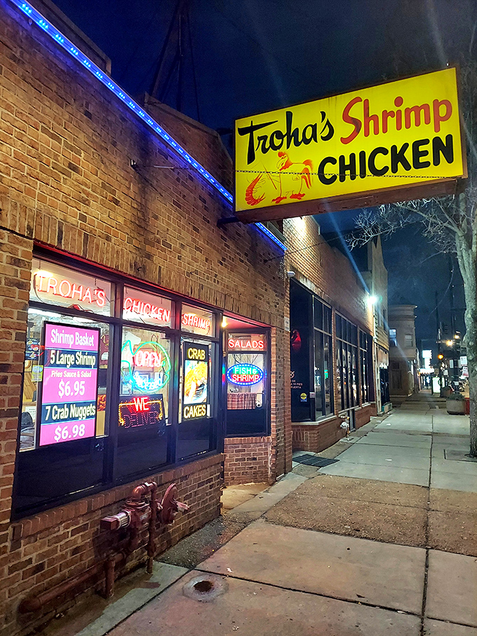 By day, it's a cheerful yellow beacon. By night, it's a neon-lit temple of fried delights. Troha's: where seafood dreams come true.
