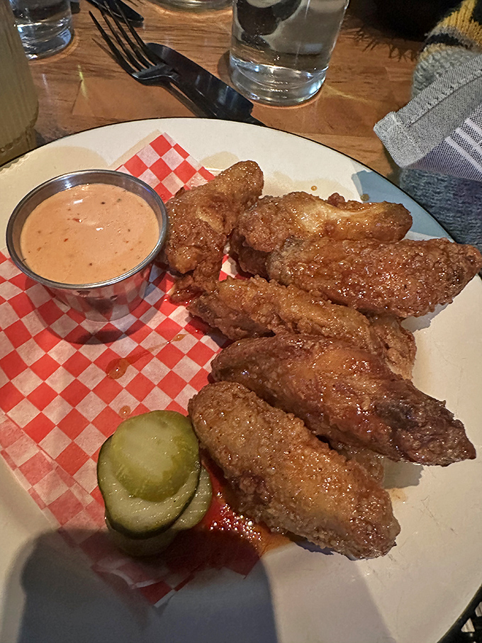 Wings served with house-made sauce, pickles, and zero pretension. The red-checkered paper says "we care about flavor, not fancy."