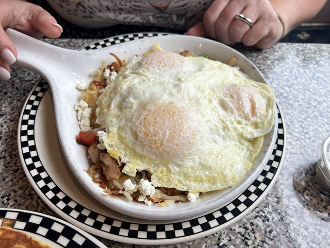 It's a skillet of dreams! Eggs perch atop a mountain of savory goodness, ready to fuel your day or cure last night's excesses.
