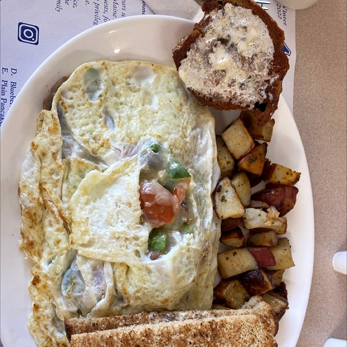 Behold, the breakfast trifecta! Golden omelet, perfectly toasted bread, and home fries that look like they're ready to steal the show. It's the holy trinity of morning meals.