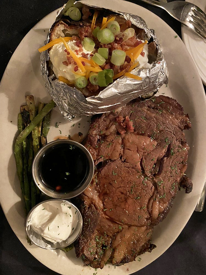 Feast your eyes on this prime rib masterpiece! It's flanked by a baked potato that's dressed to impress and veggies that add a pop of color to this meaty canvas.