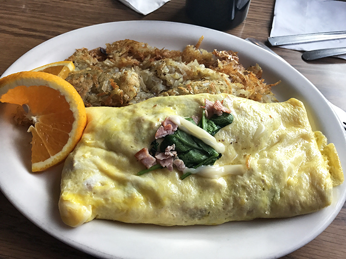 Breakfast perfection on a plate: golden hash browns, a fluffy omelet, and ham that could make a vegetarian reconsider their life choices.