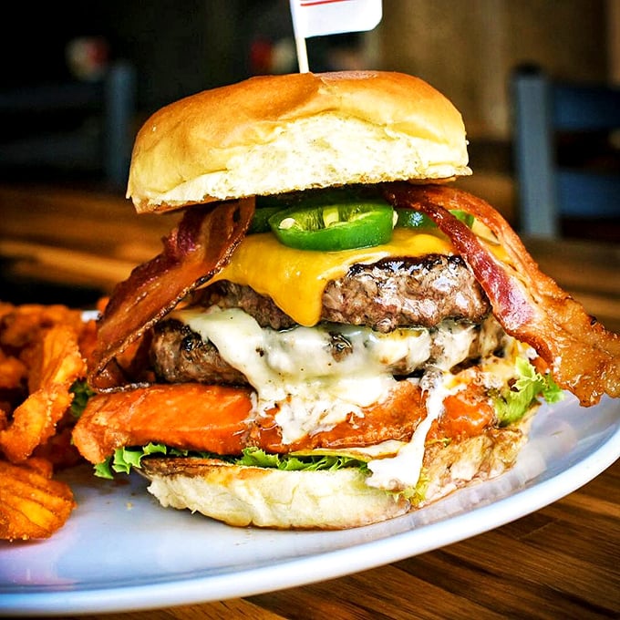 Behold, the Leaning Tower of Deliciousness! This burger defies both gravity and your willpower to resist its meaty, cheesy charms.