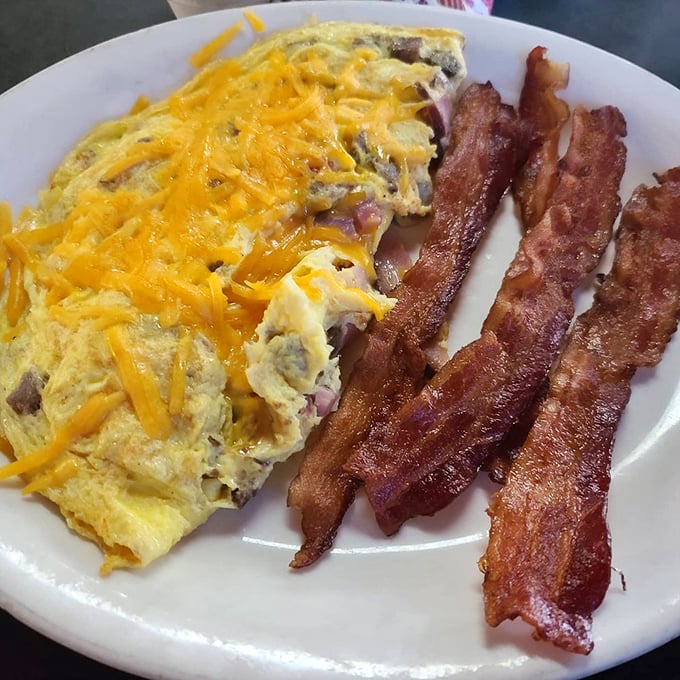 This isn't just an omelet &ndash; it's a cheese-crowned celebration of morning possibilities, with bacon standing guard like delicious sentinels.