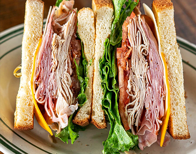 This club sandwich isn't just stacked; it's a skyscraper of flavor. Each layer a new adventure, it's the Empire State Building of lunch options.