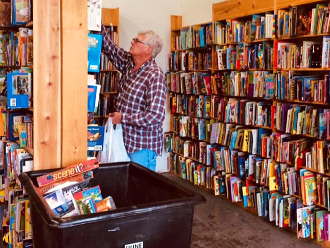 The thrill of the hunt! This gentleman embodies the spirit of every book lover, reaching for that elusive tome just out of grasp.