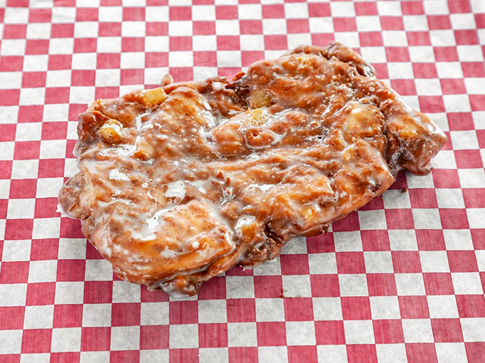This apple fritter on classic red-and-white checkered paper isn't just a donut&mdash;it's edible architecture with valleys of cinnamon and peaks of glaze.