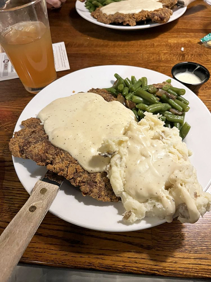 Country-fried steak swimming in velvety gravy beside creamy mashed potatoes and green beans&mdash;comfort food that whispers, "Take a nap after this, you'll need it."