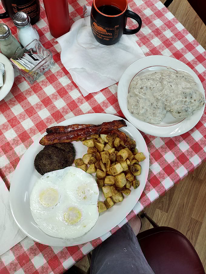 The breakfast trinity: perfectly cooked eggs, crispy bacon, and golden hashbrowns, with a side of biscuits that could make your grandmother jealous.