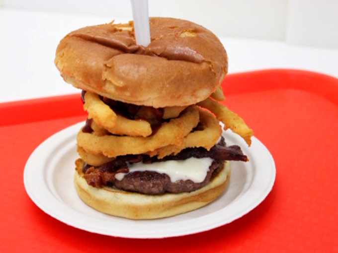 Hold onto your taste buds! This towering burger creation is like the Leaning Tower of Deliciousness, complete with a crispy onion ring crown.