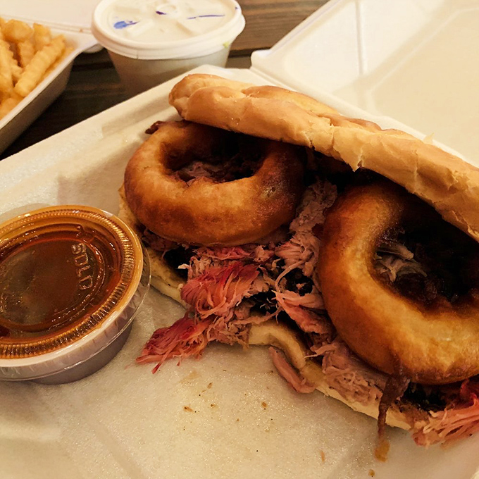 The pulled pork sandwich with onion rings&mdash;where the humble pig achieves its highest calling between bread, with golden rings standing guard like delicious sentinels.