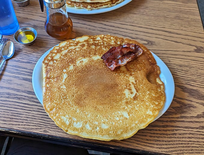 Pancakes so big, they should come with their own zip code. That bacon on top? Just the cherry on this breakfast sundae.
