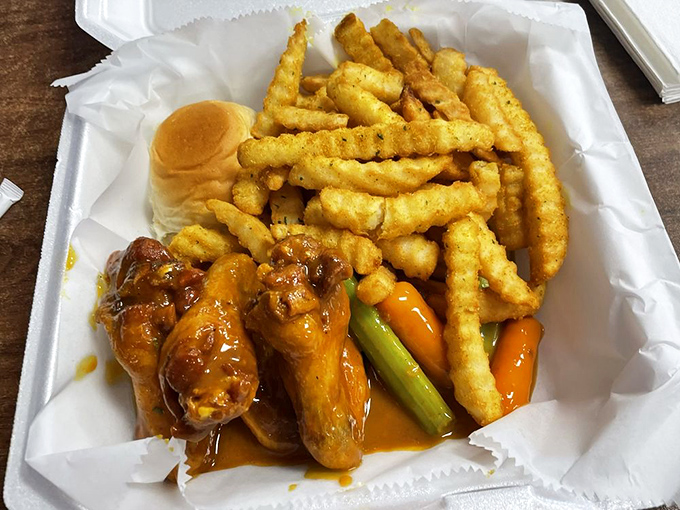 A complete meal deal: wings, fries, celery, carrots, and a roll to sop up any leftover sauce. Nothing goes to waste here.