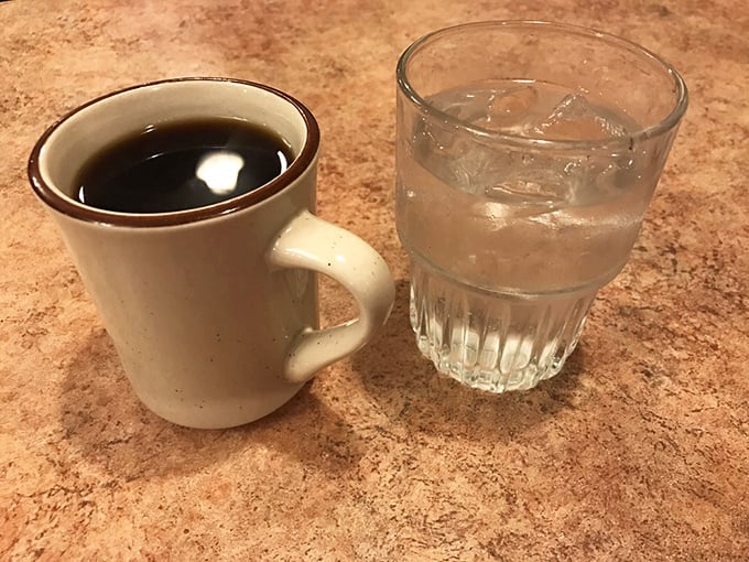 The classic diner duo: sturdy ceramic mug of coffee black as midnight, water glass perpetually full. Simple pleasures, perfectly executed.