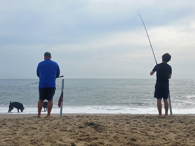 The ultimate waiting game: Two men, a dog, and the vast ocean. It's like a zen garden, but with the possibility of dinner.