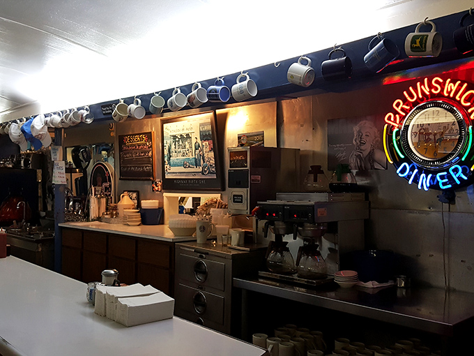 Coffee mugs hang like trophies above the counter, where the neon sign glows with the promise of meals worth remembering.