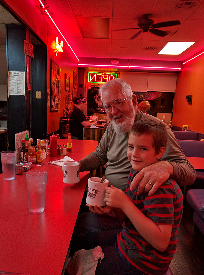 Three generations sharing coffee in that distinctive red glow&mdash;this isn't just breakfast, it's inheritance of tradition.