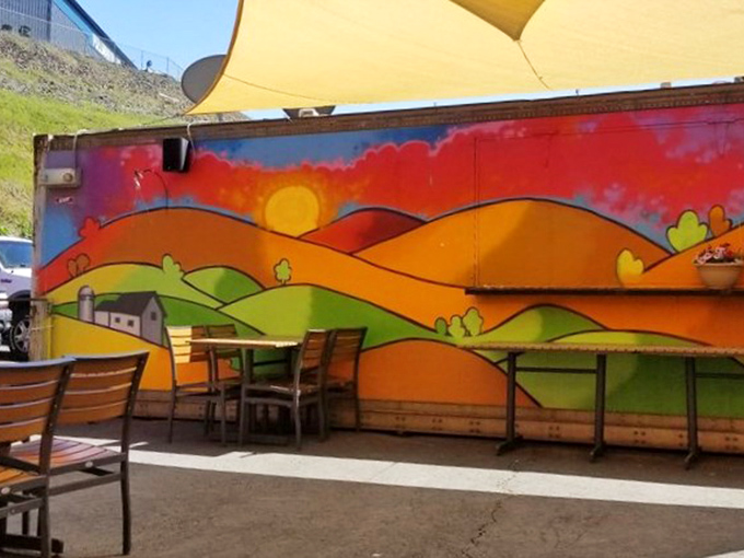 The outdoor seating area feels like a secret garden with that whimsical mural&mdash;the kind of place where afternoon drinks mysteriously turn into evening plans.
