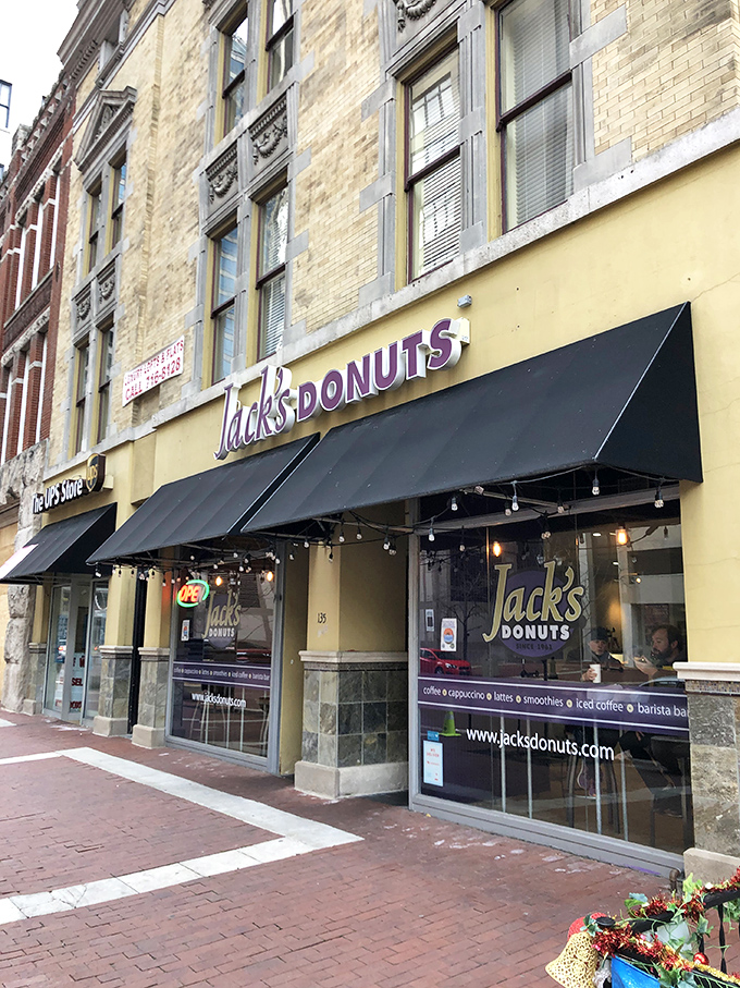 Jack's Donuts announces its presence with charming simplicity—a yellow brick building, black awning, and the promise of sweet satisfaction waiting inside.