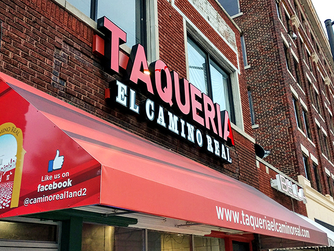 The glowing red "TAQUERIA" sign against brick isn't just signage&mdash;it's a beacon of hope for hungry souls seeking authentic Mexican flavors in Kansas City.