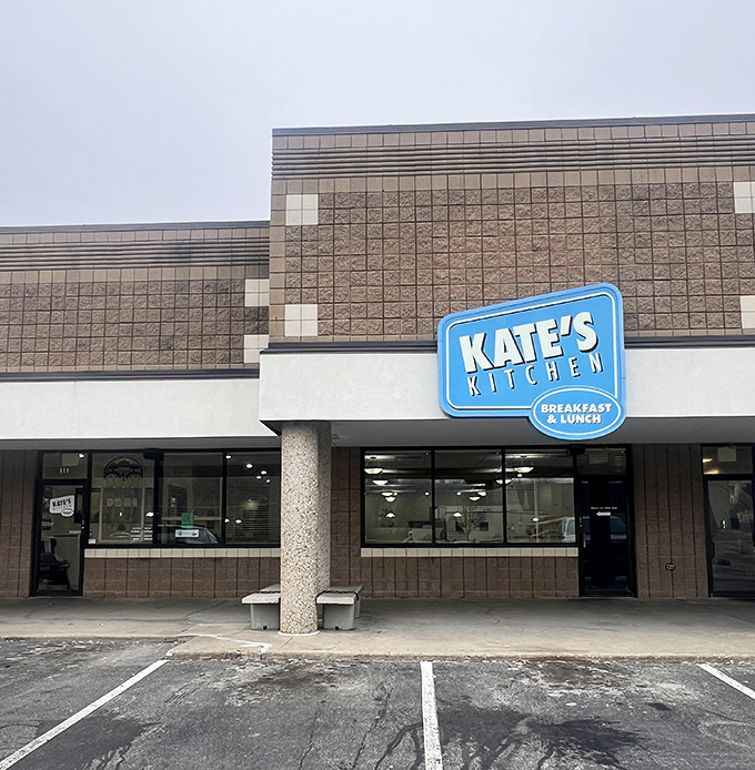 The blue sign beckons like a breakfast lighthouse, guiding hungry souls to Kate's Kitchen where morning miracles await in tortilla-wrapped glory.