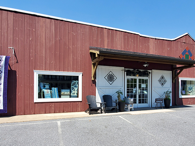 The iconic red barn exterior of Log Cabin Quilt Shop welcomes fabric enthusiasts with its charming quilt block displays—a colorful beacon for crafters in Amish Country.
