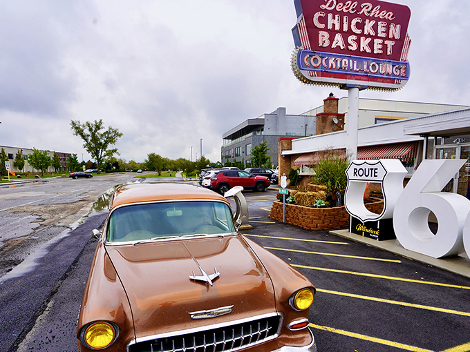 The iconic neon sign and Route 66 shield welcome hungry travelers like a beacon of fried chicken salvation. Classic cars occasionally grace the parking lot, completing the time-travel experience.