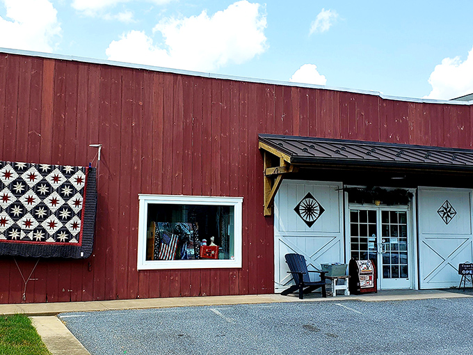 The iconic red barn exterior of Log Cabin Quilt Shop welcomes fabric enthusiasts with its charming quilt block displays&mdash;a colorful beacon for crafters in Amish Country.