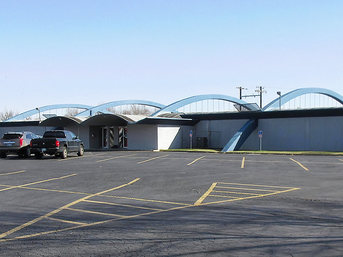 The distinctive blue arches of Holiday Lanes stand like a mid-century monument to fun, practically winking at this vintage camper parked outside.