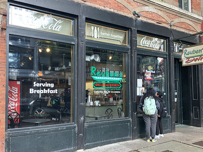The historic brick façade of Reuben's Deli stands as a beacon for sandwich aficionados. That vintage sign promises delicious things await inside.