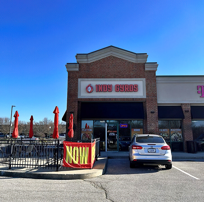 The brick fa&ccedil;ade of Indy Gyros stands like a beacon of Mediterranean hope in a sea of chain restaurants. Those red umbrellas practically whisper, "Slow down, hungry traveler."