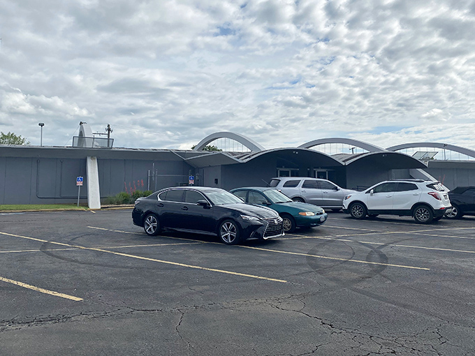 The distinctive blue arches of Holiday Lanes stand like a mid-century monument to fun, practically winking at this vintage camper parked outside. 
