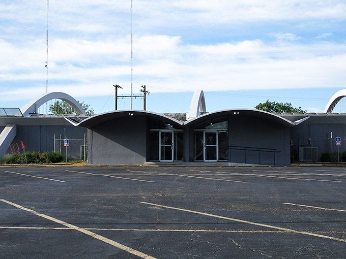 The distinctive blue arches of Holiday Lanes stand like a mid-century monument to fun, practically winking at this vintage camper parked outside. 