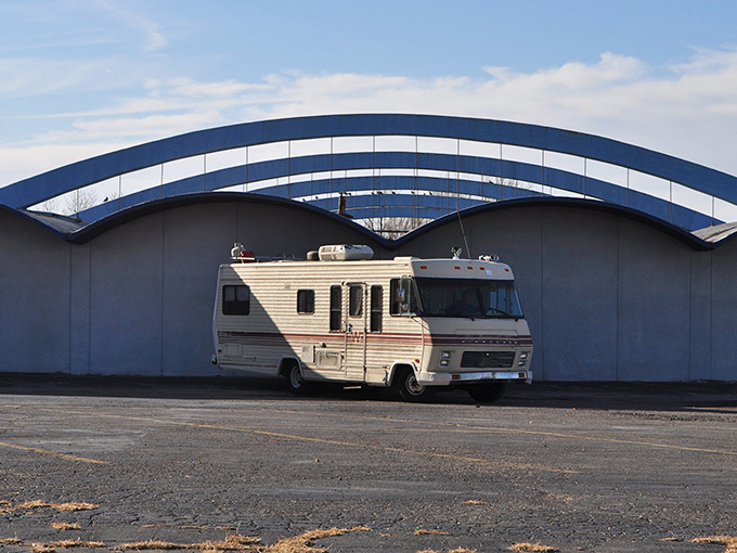 The distinctive blue arches of Holiday Lanes stand like a mid-century monument to fun, practically winking at this vintage camper parked outside.