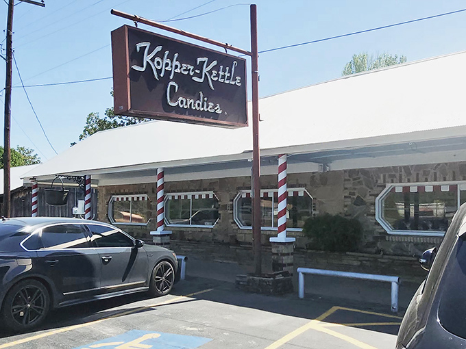 The iconic storefront of Kopper Kettle Candies stands resilient against Arkansas rain, its candy-striped poles promising sweet refuge from ordinary life.