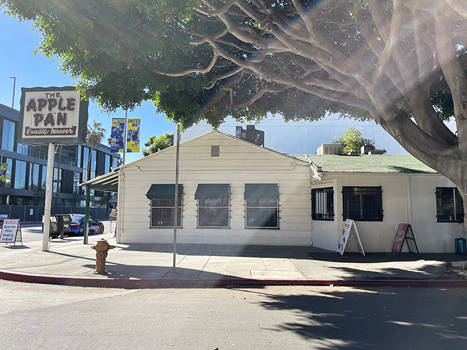 The unassuming white exterior of The Apple Pan stands like a time capsule on Pico Boulevard, its iconic sign promising "Quality Forever" beneath LA's blue skies.