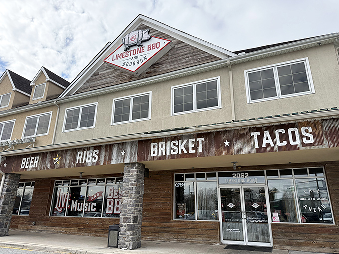 The rustic exterior of Limestone BBQ and Bourbon beckons like a smoke signal to hungry travelers. Corrugated metal and warm wood promise authentic barbecue treasures within.