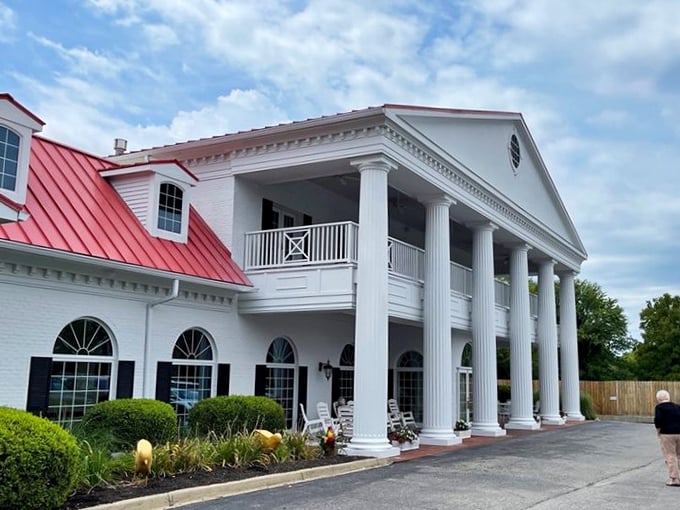The white colonial mansion with its distinctive red roof stands as a beacon of Southern hospitality, promising culinary treasures within its historic walls.