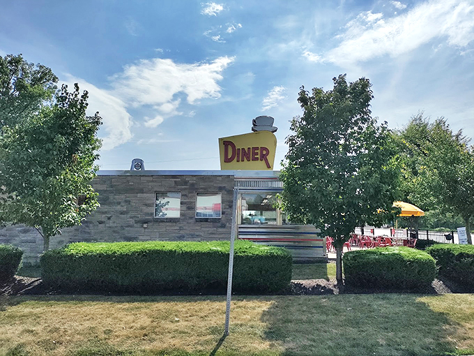 The classic stainless steel and stone exterior of The Oasis Diner stands like a time capsule on Plainfield's landscape, its iconic yellow sign beckoning hungry travelers.