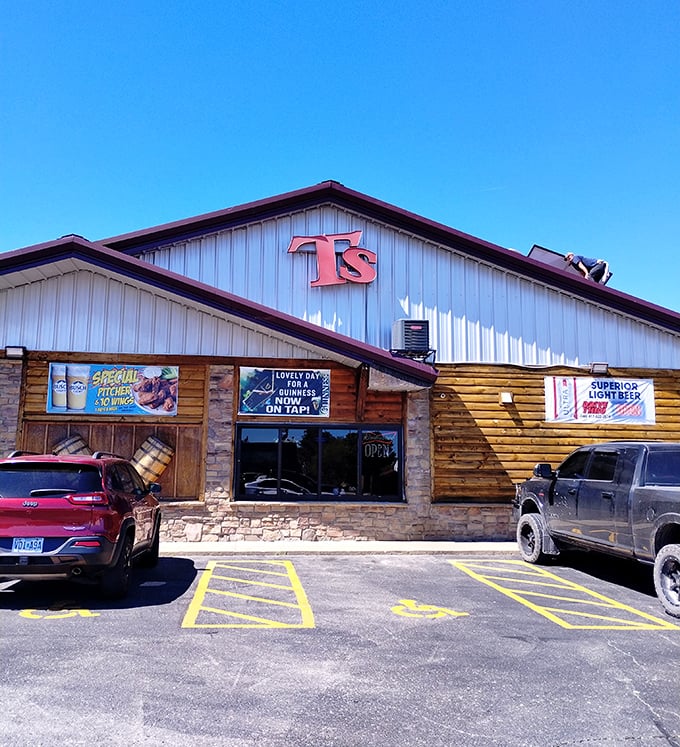 The log cabin exterior of T's Redneck Steakhouse glows with warm invitation as dusk settles, promising carnivorous delights within those rustic walls. 