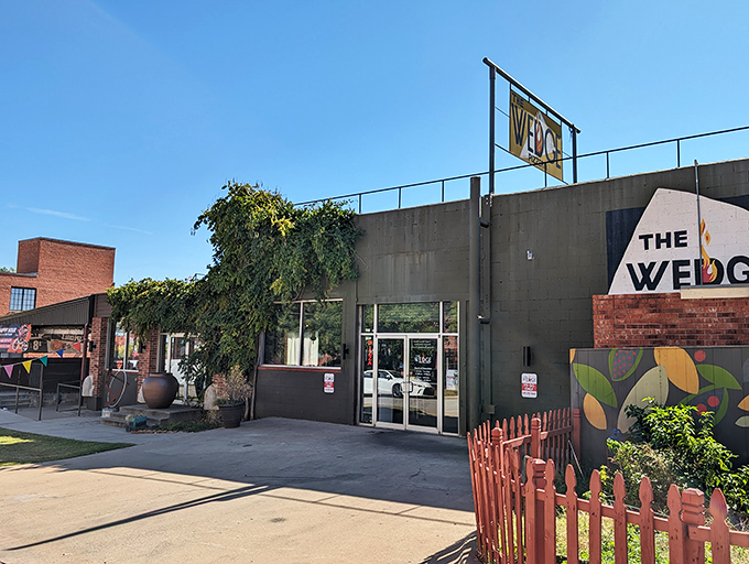 The Wedge's exterior is like a colorful storybook come to life. That vibrant orange fence and playful mural practically scream "good times and great pizza await inside!"