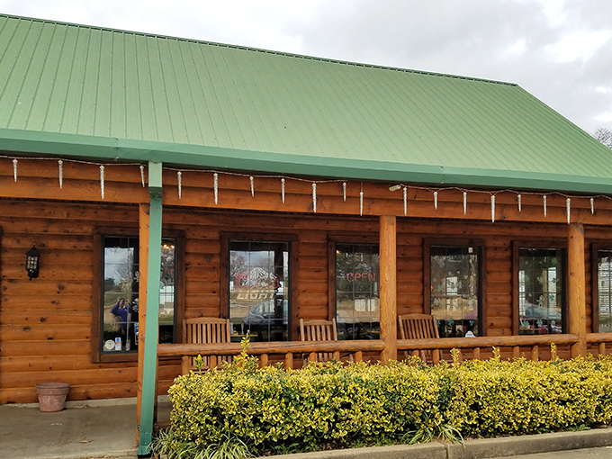 The log cabin exterior of Oaks Steak House welcomes hungry travelers with its distinctive green roof and rustic charm. Oklahoma hospitality in architectural form.