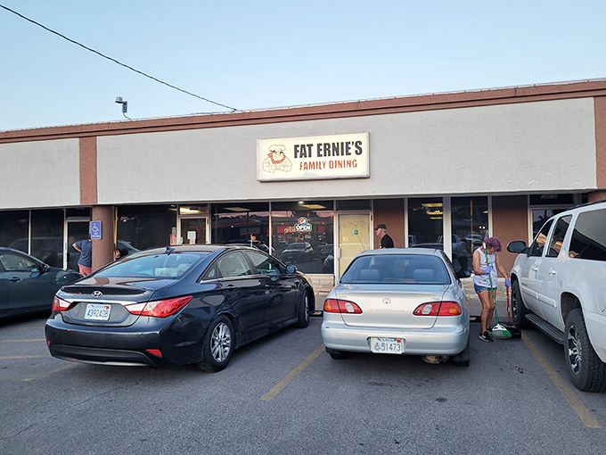 The unassuming exterior of Fat Ernie's Family Dining &ndash; where culinary treasures hide behind beige walls and a cartoon chef who seems to know something you don't.