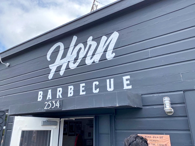 The unassuming exterior of Horn BBQ in Oakland &ndash; where that bold white lettering against dark panels is the architectural equivalent of a whisper about the best-kept secret in town.