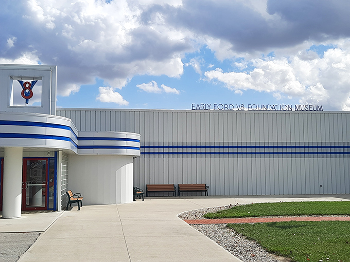 The sleek Art Deco-inspired exterior of the Early Ford V-8 Museum beckons car enthusiasts with its distinctive blue striping and retro styling. Automotive heaven awaits.