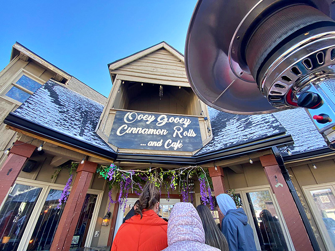 The charming cottage-style exterior of OoeyGooey beckons with bright red umbrellas and rustic wooden tables, promising sweet treasures within.