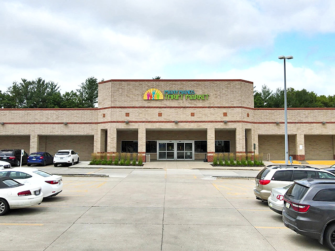 The bright yellow logo featuring colorful hands reaching skyward welcomes bargain hunters like a thrifting bat signal against Clive's clear blue skies.