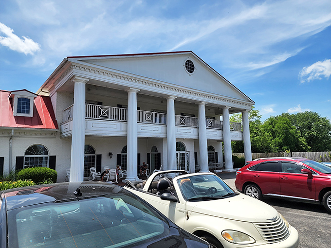 The white colonial mansion with its distinctive red roof stands as a beacon of Southern hospitality, promising culinary treasures within its historic walls.