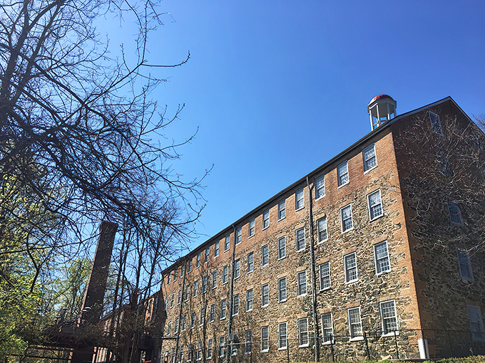The historic brick exterior of Savage Mill welcomes treasure hunters with its distinctive blue awning&mdash;industrial architecture transformed into an antiquing paradise.