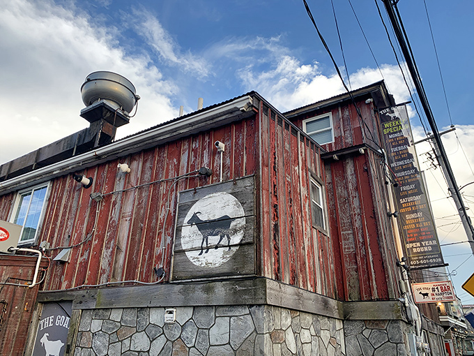 The weathered wooden exterior of The Goat stands proudly against Hampton's skyline, like a delicious pirate ship that decided to drop anchor and serve burgers instead.